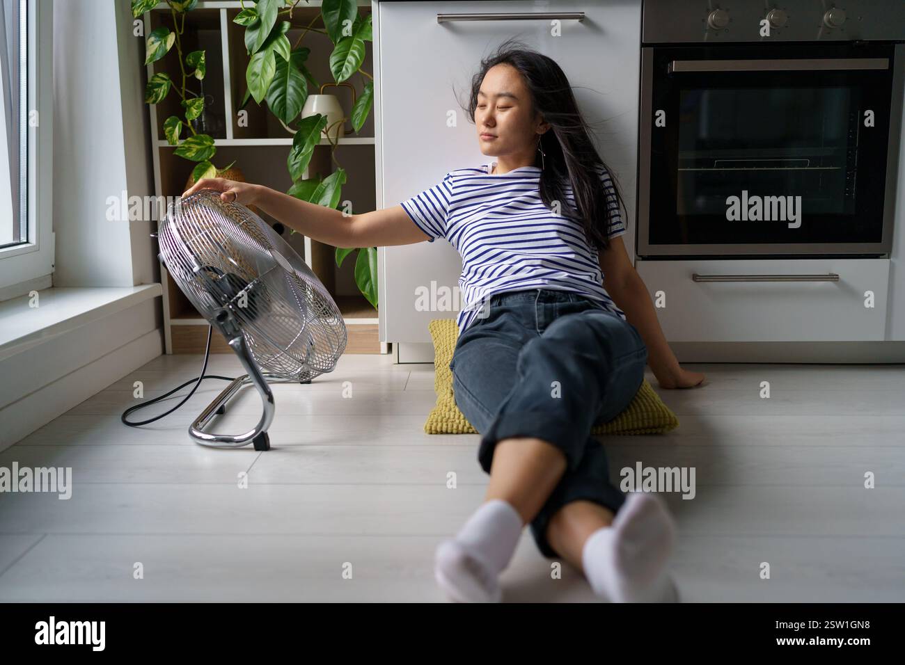 Tired overheated young Asian woman suffering from heat at home Stock ...