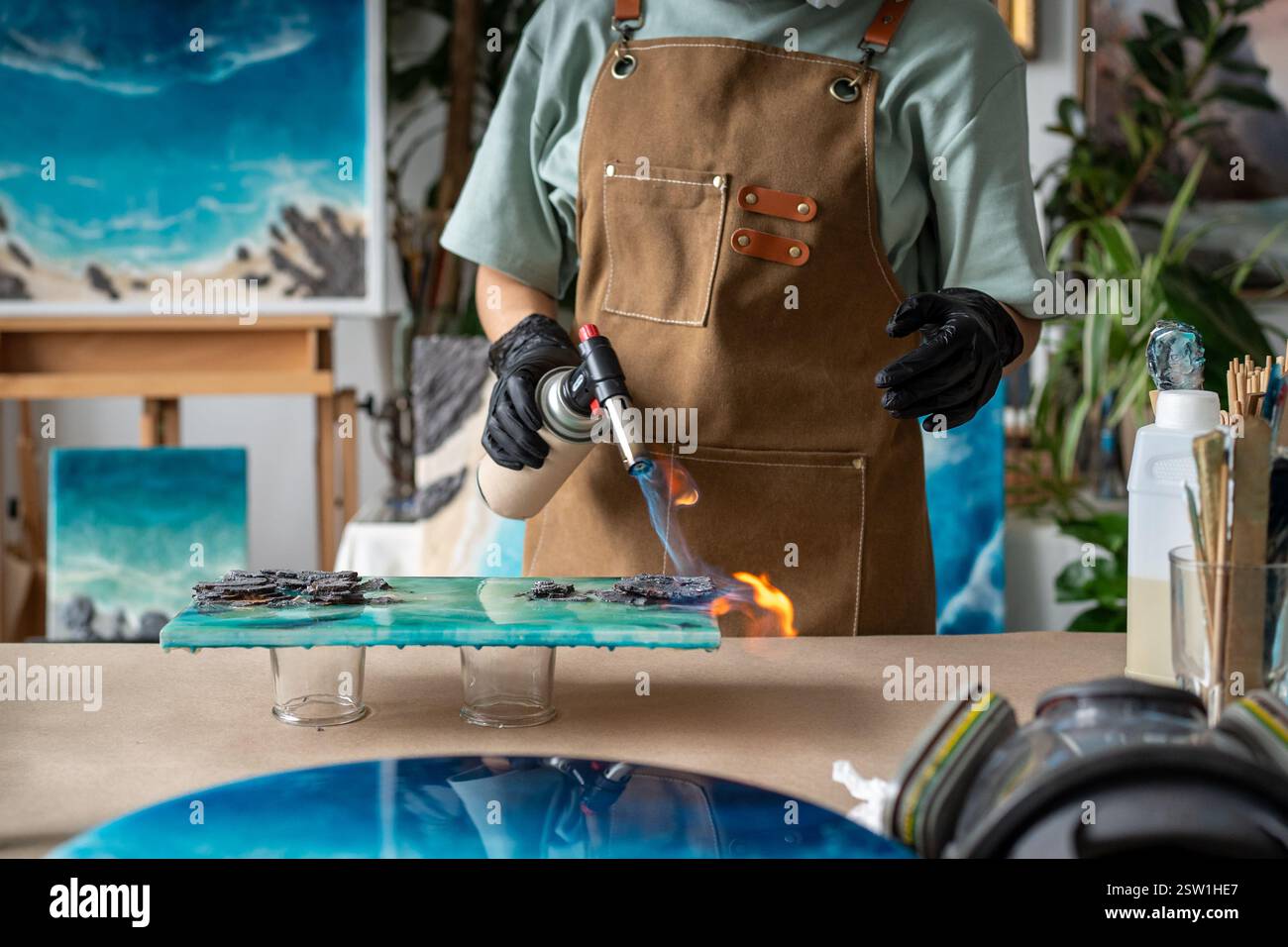 Hands of female artist burn epoxy resin painting with blowtorch hi-res ...