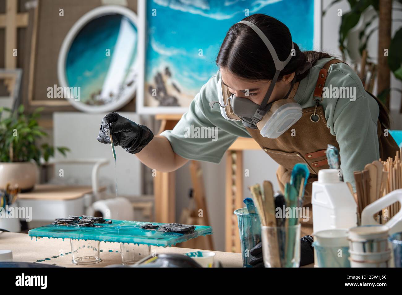 Attentive thorough woman working carefully with epoxy resin, creating ...