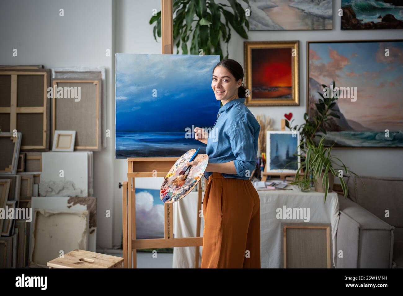 Joyful woman artist working on oil painting. Smiling joyous creative ...