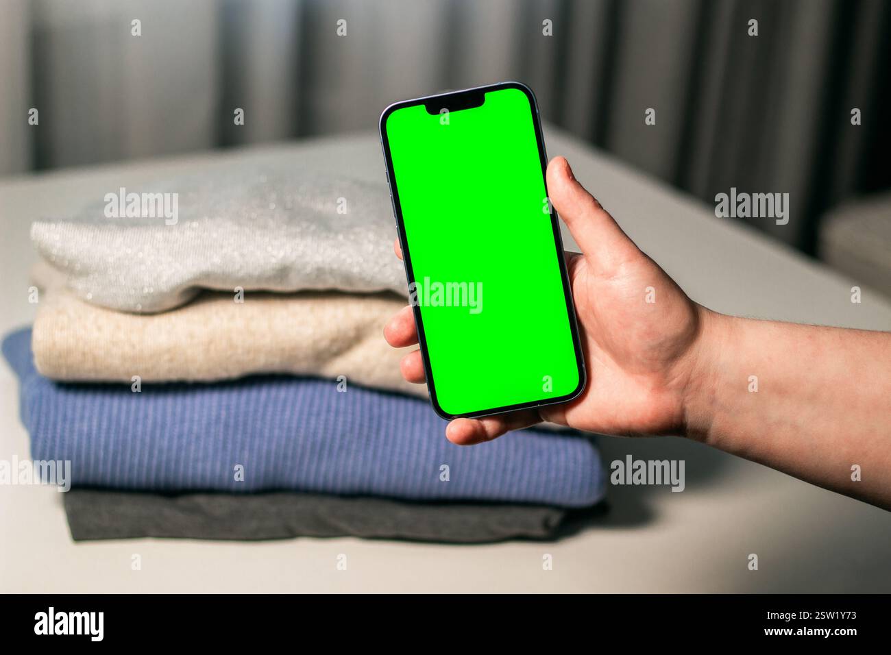 Smartphone with blank screen with stack of clothes illustrating second ...
