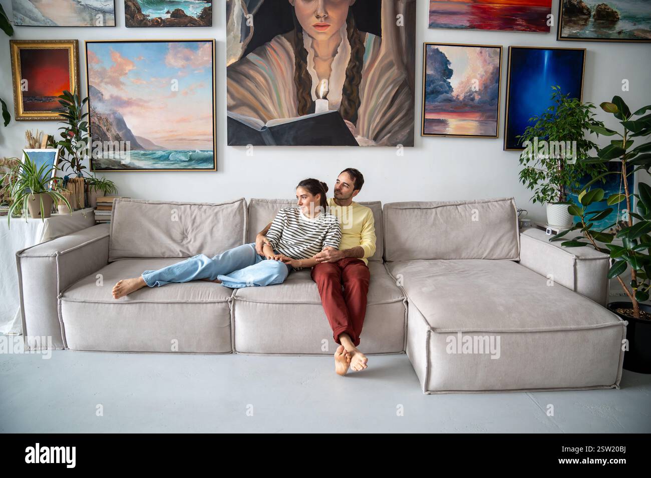 Happy relaxed loving couple rest on couch in home art gallery hugging ...