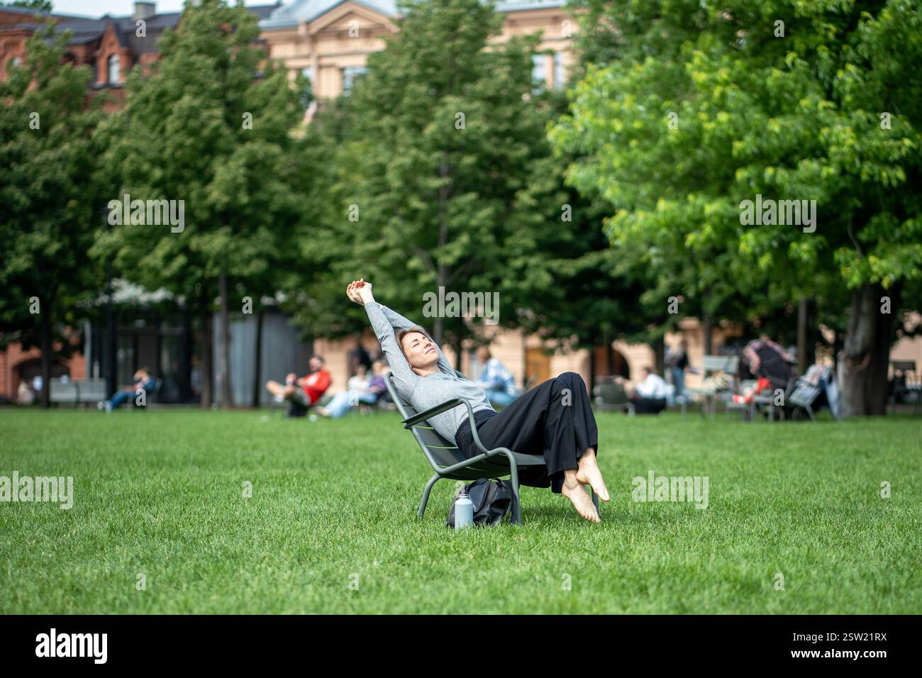 Laid-back lazy and drowsy woman stretching and napping in park lounger ...