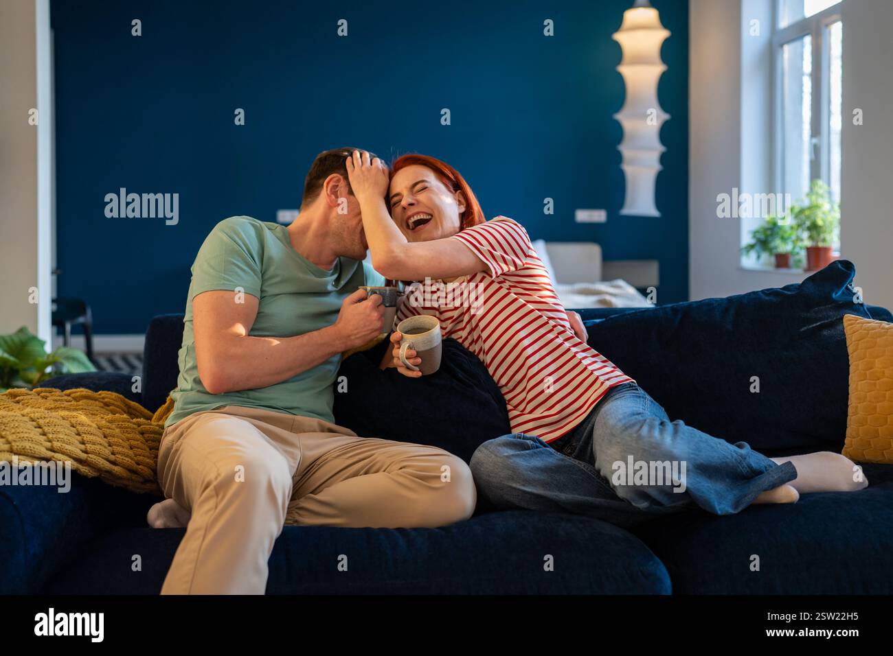 Happy married couple sitting on couch laughing together. Overjoyed ...