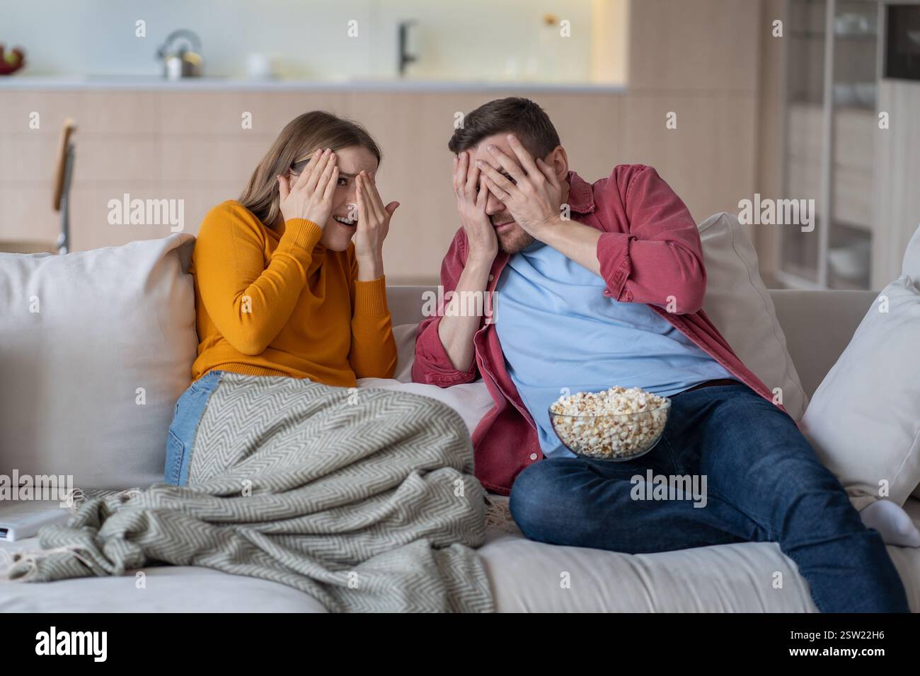 Fearful married couple, husband wife sitting on couch scared by ...