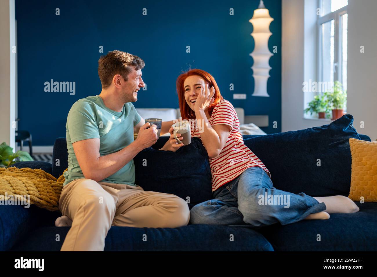 Happy laughing couple wife and husband drinking tea coffee from cups ...