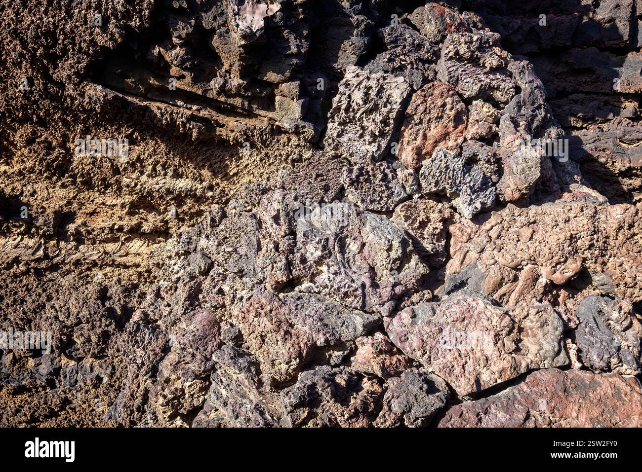 Close up of a lava flow that has solidified with multiple colours and ...