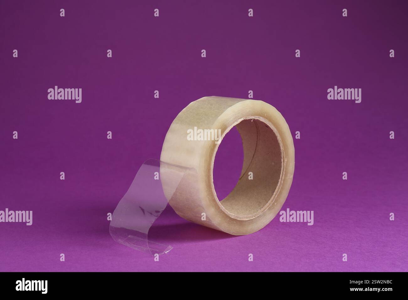 Roll of adhesive tape on violet background Stock Photo - Alamy
