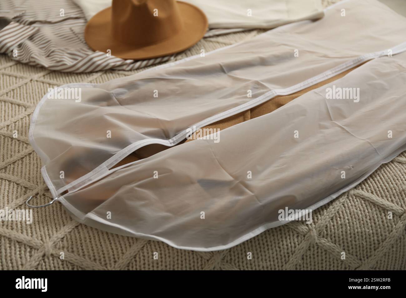 Garment cover with clothes on bed indoors, closeup Stock Photo - Alamy