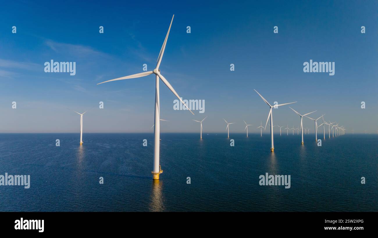 Tall windmills stand elegantly against the serene waters, creating a ...