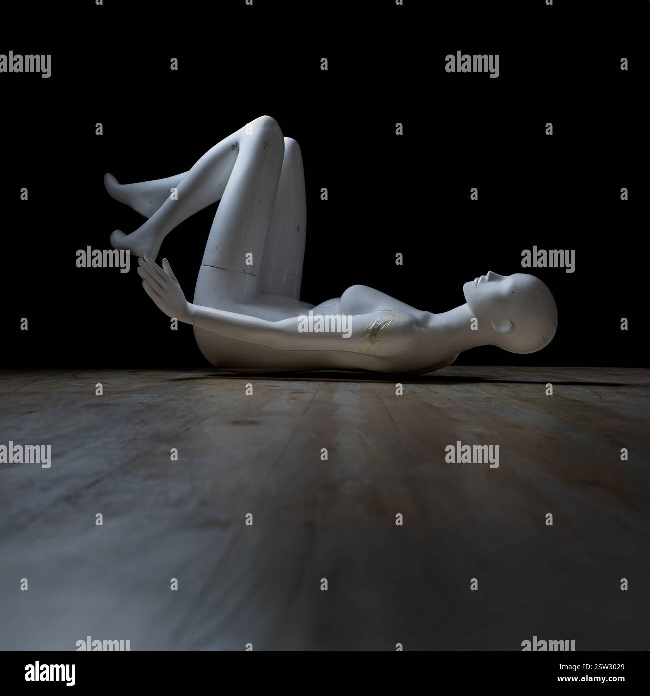 Life-size white fibreglass mannequin lying back flat against a wooden ...