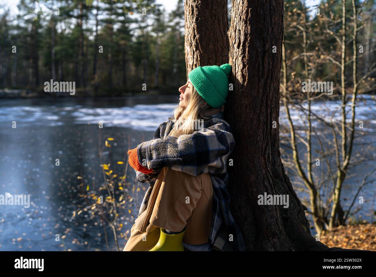 Relaxed calm woman sitting leaning on tree breathing fresh air in fall ...