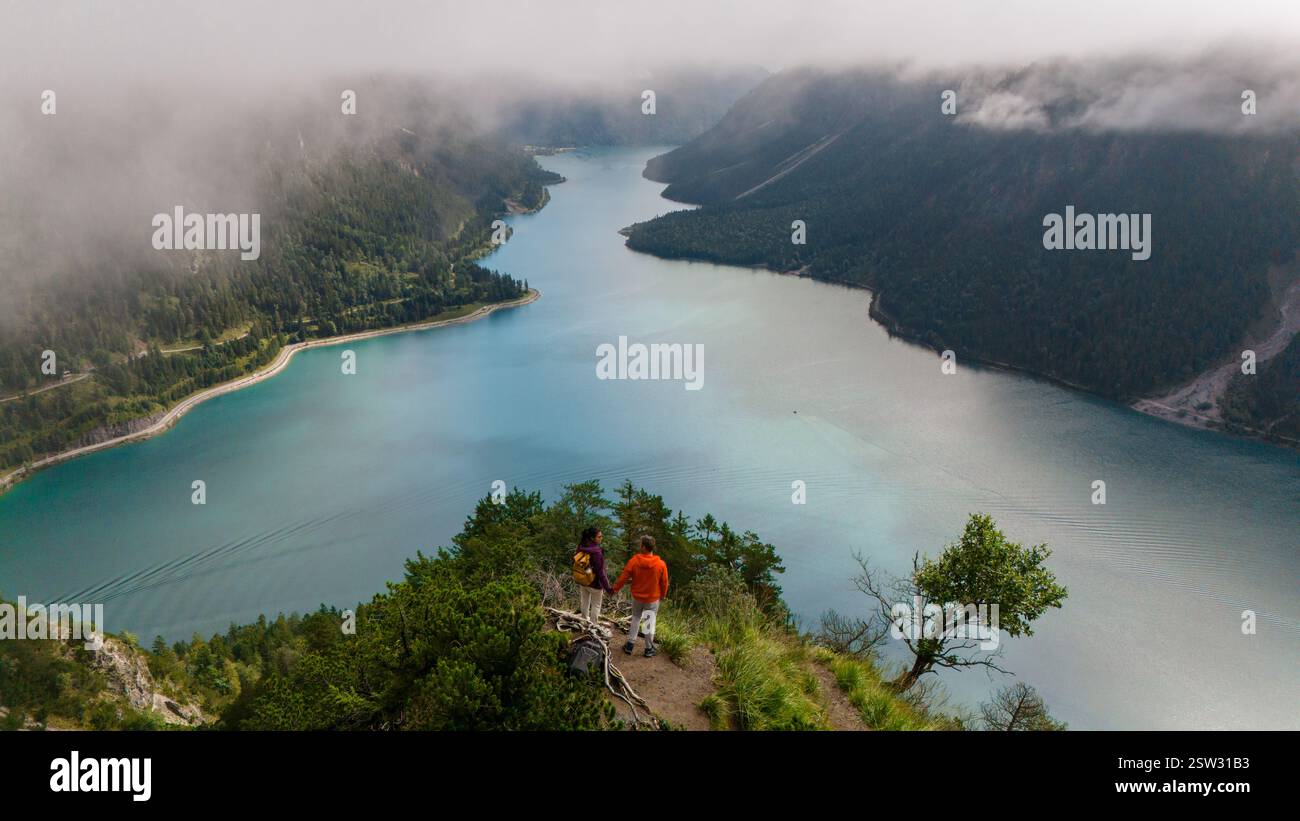 Stunning view of Plansee lake in Austria shrouded in mist with hikers ...