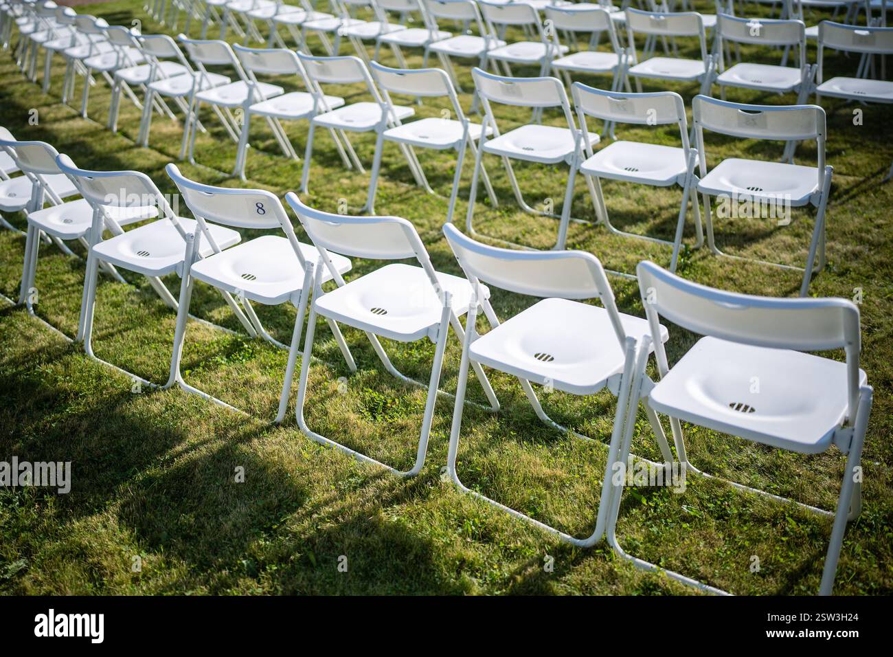 Empty folding chairs stand in rows on green grass hi-res stock ...