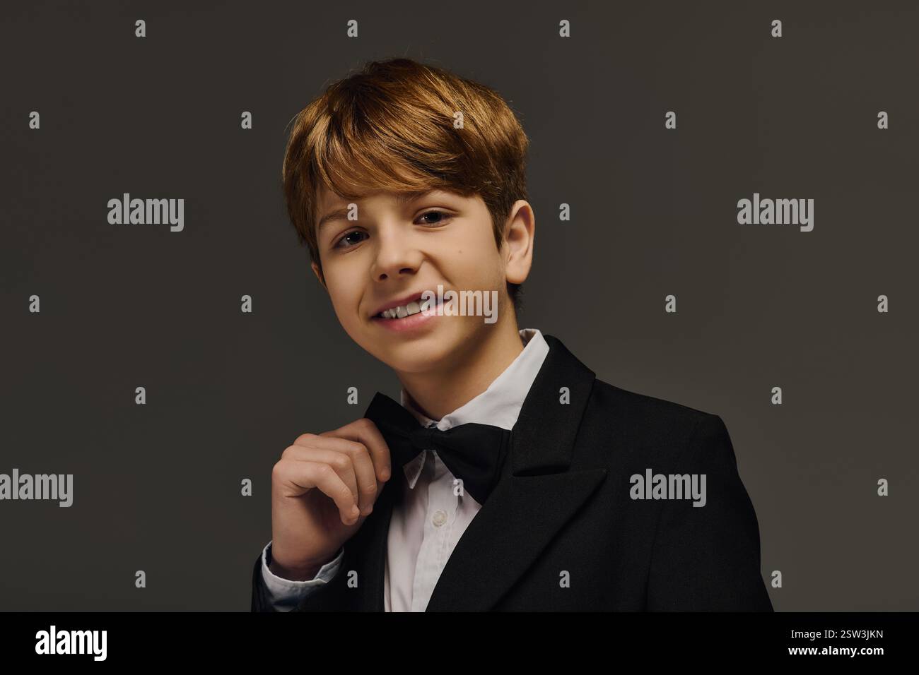 Dressed in a sleek tuxedo and bow tie, a preteen boy exudes confidence ...