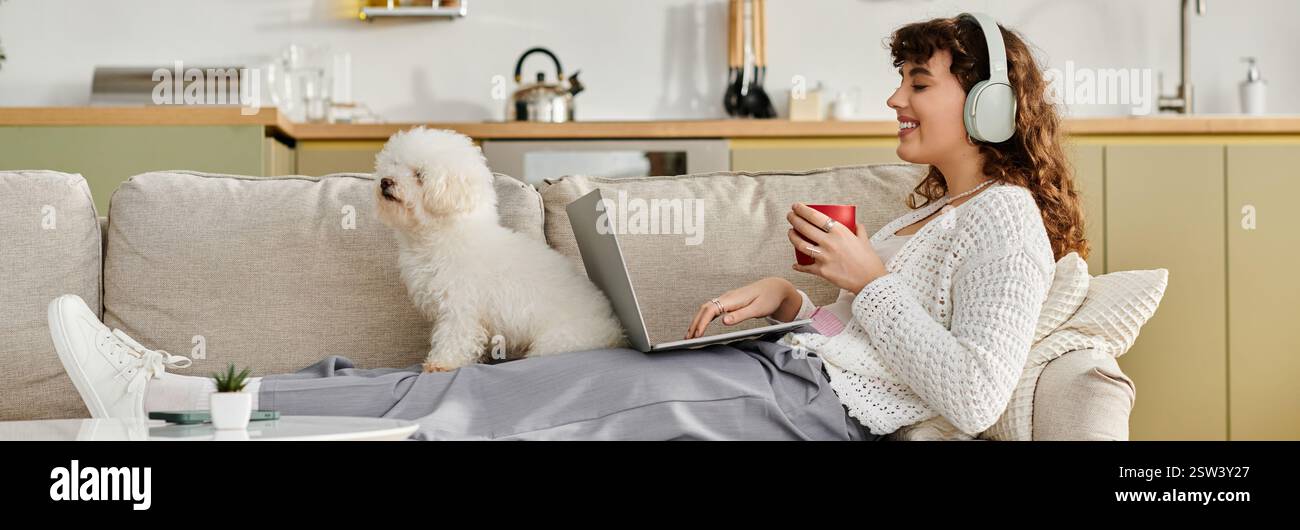 Relaxing in a comfortable living room, a young woman sips a warm drink ...