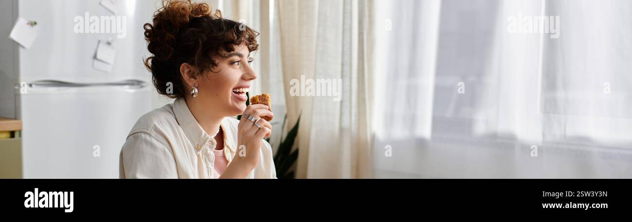 A happy woman enjoys a delicious treat in her sunny, warm kitchen Stock ...