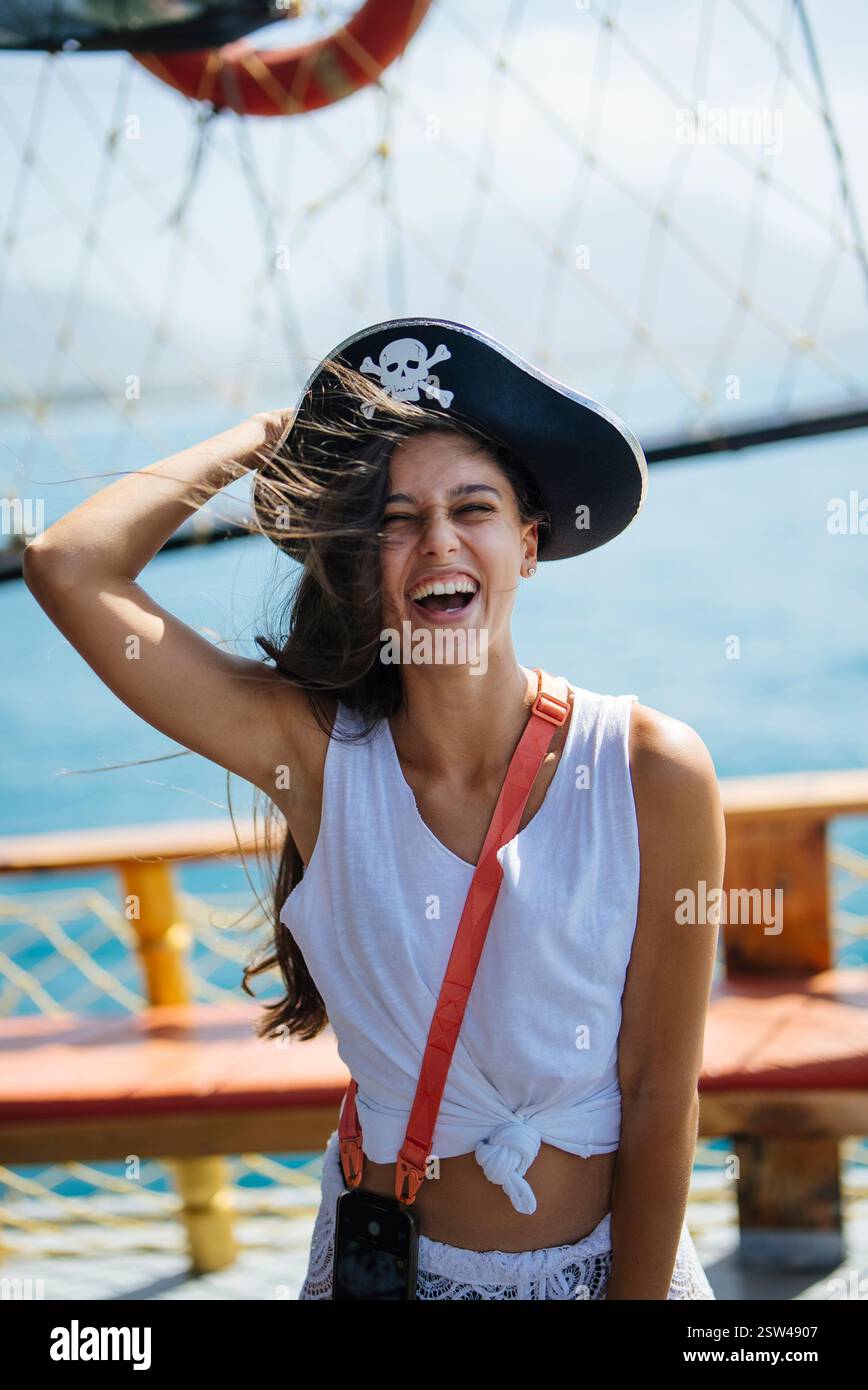 A young woman, playfully dressed as a pirate, joyfully poses on a ...