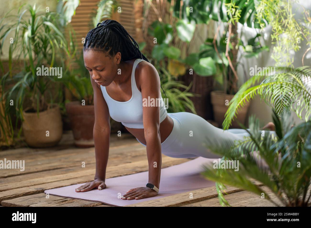 Focused on breath active black woman doing plank on fitness mat with ...