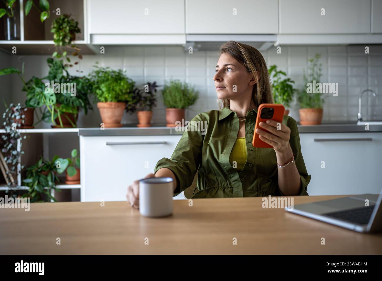 Thoughtful woman drinking tea during work break, looking at window ...