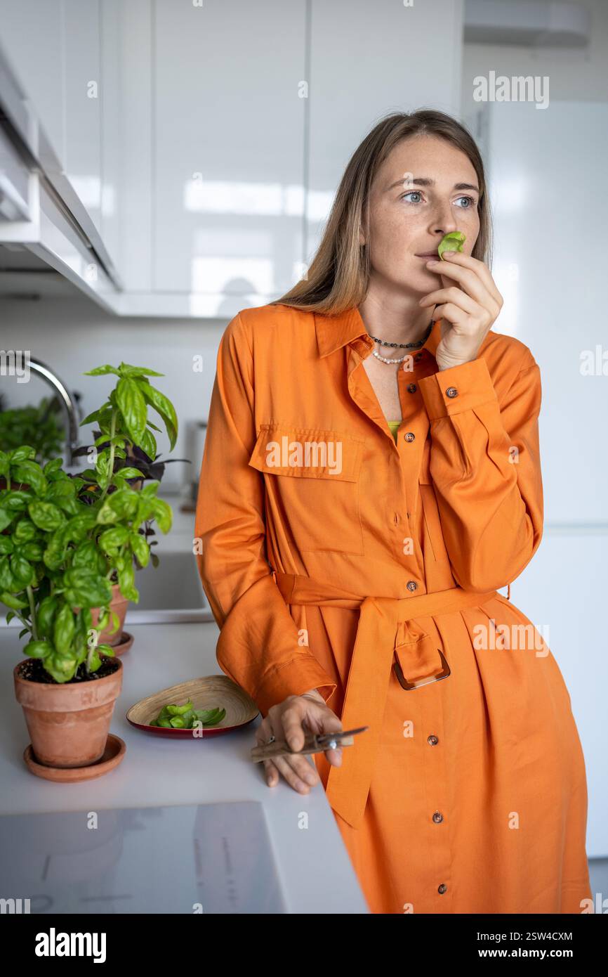 Woman sniffs home-grown basil leaf. Female gardener enjoying smell of ...