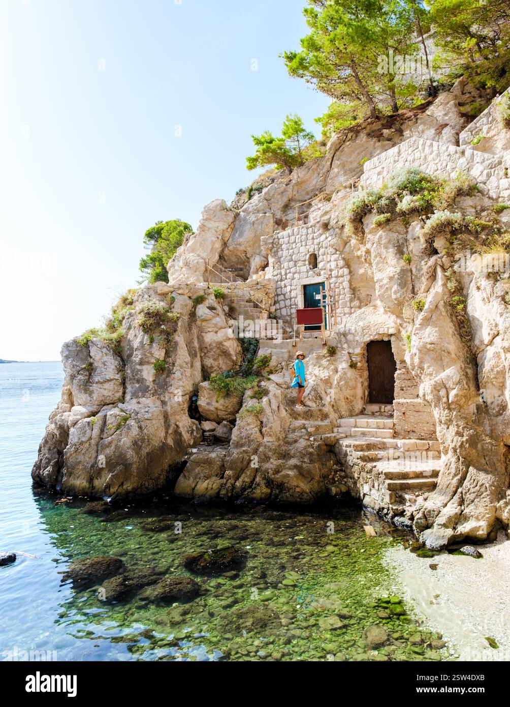 A woman ascends stone steps leading from tranquil shoreline, surrounded ...