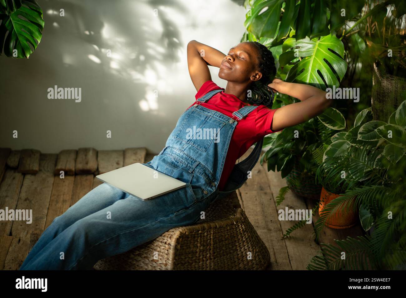 Relaxed freelancer black woman rest after work on chair with laptop on ...