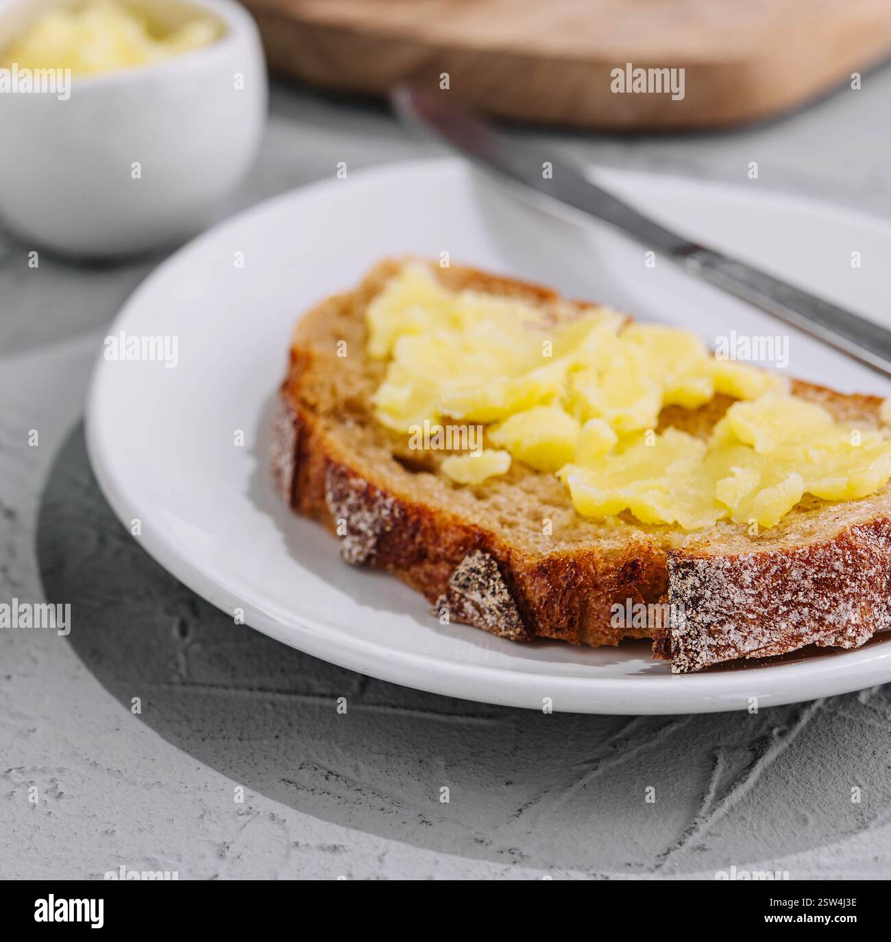 A knife spreading melted butter on bread Stock Photo - Alamy