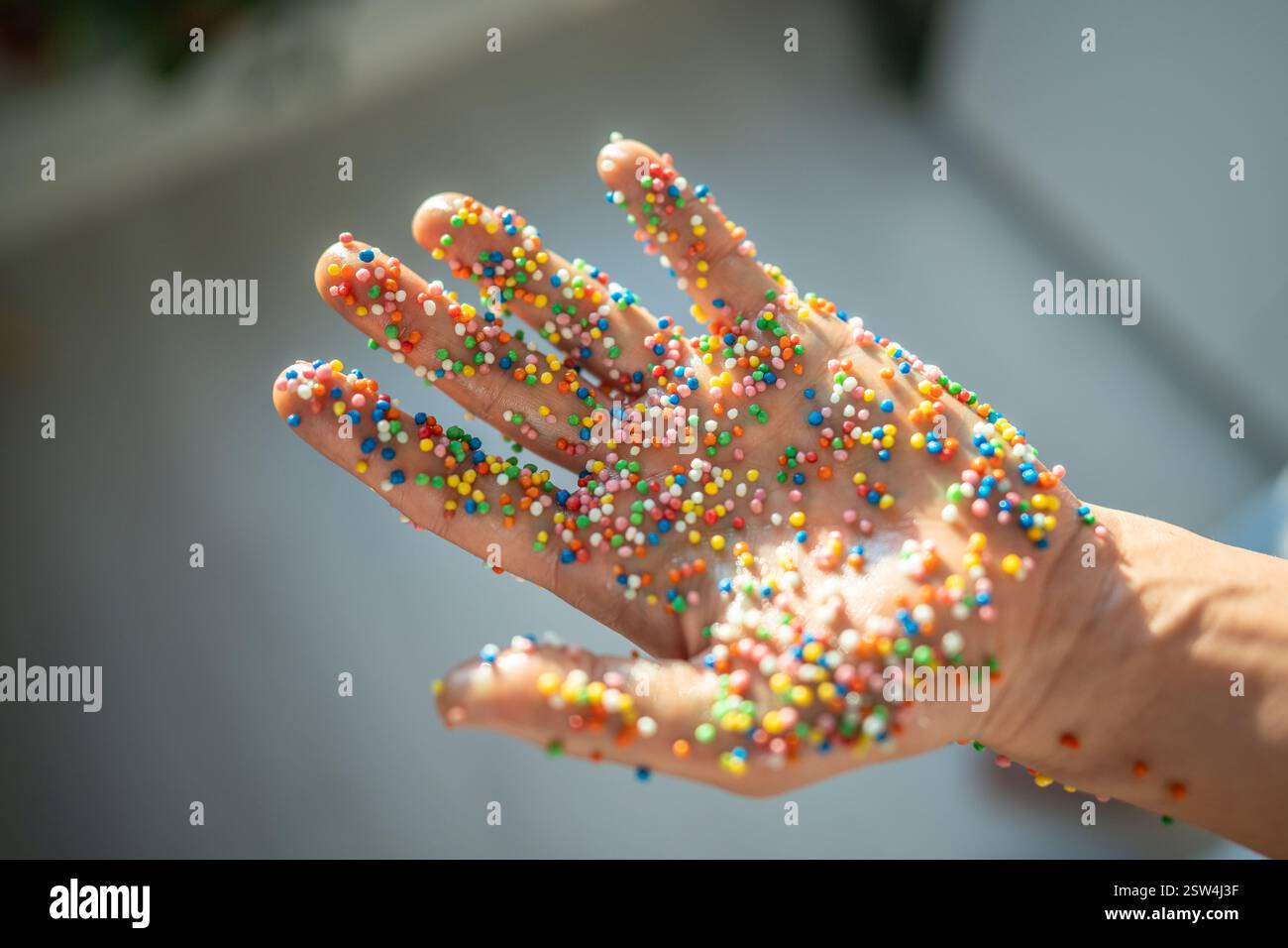 Sticky confectionary hand with colorful pastry sprinkles for baking ...