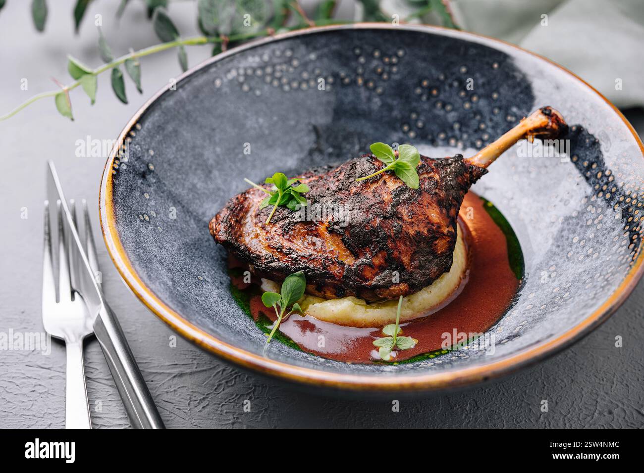 Exquisite duck confit served on creamy puree with a modern dark ceramic ...