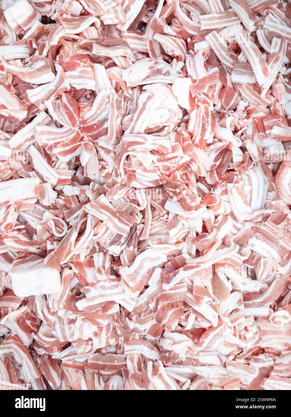 A close-up of freshly sliced pork belly arranged in a metal tray, ready ...