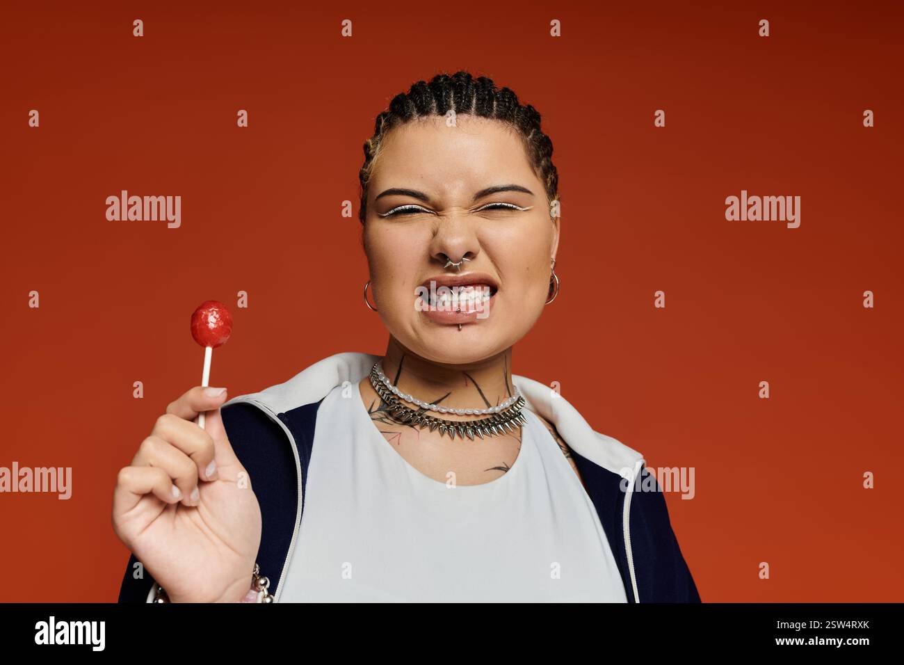 Stylish woman with bright braids smiles playfully while holding a red ...