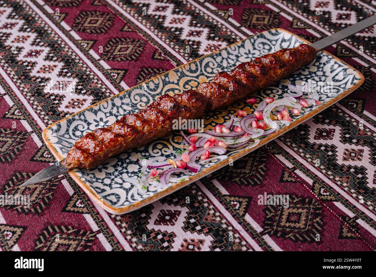 Authentic grilled kebab served with onion salad on a decorative plate ...