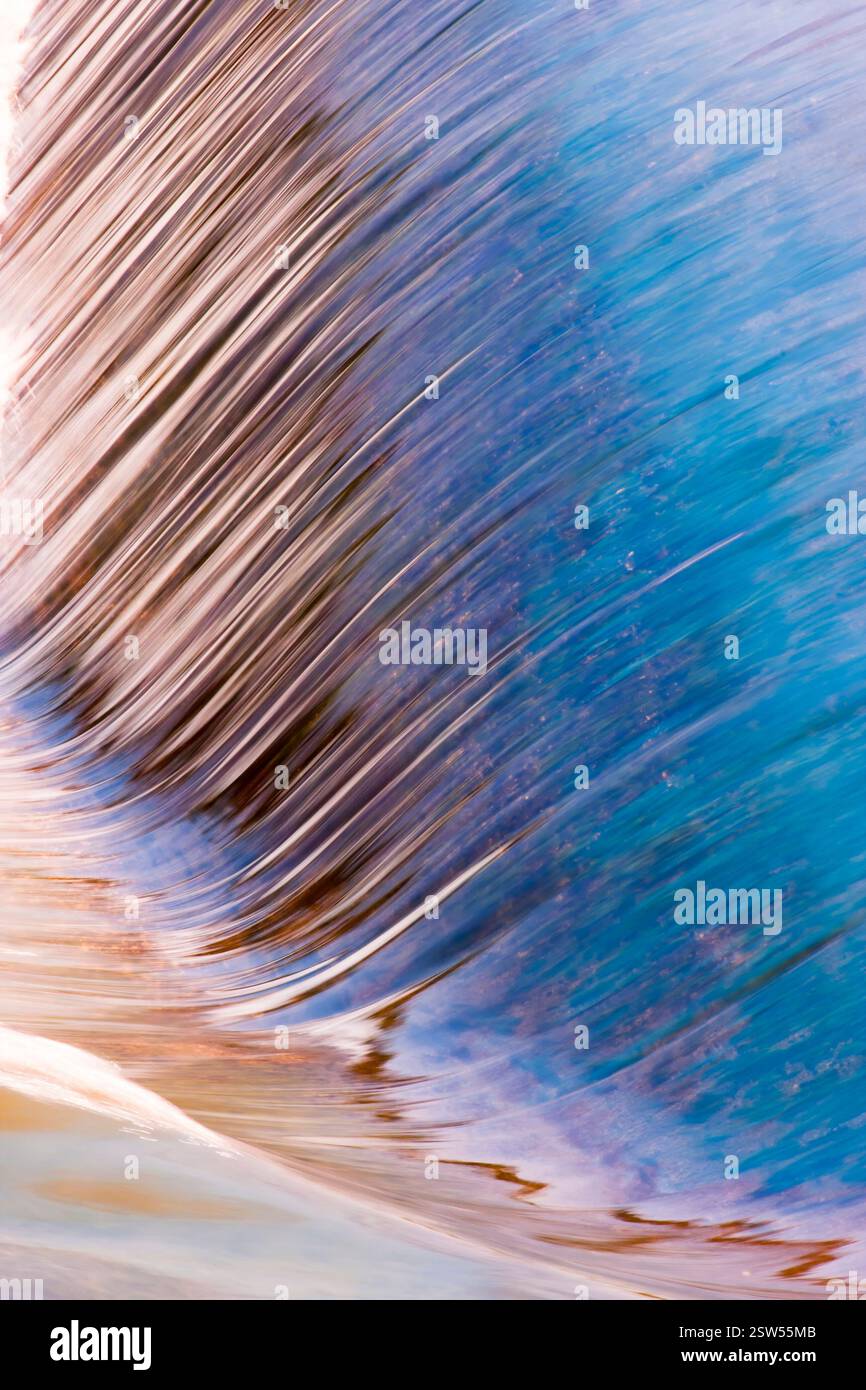 The image is a beautiful blue wave with a pinkish hue. The water is ...