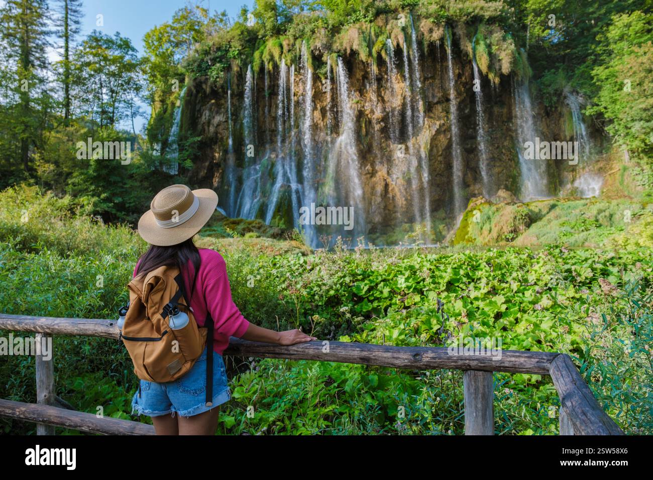 A traveler admires the stunning waterfalls cascading over rocky cliffs ...