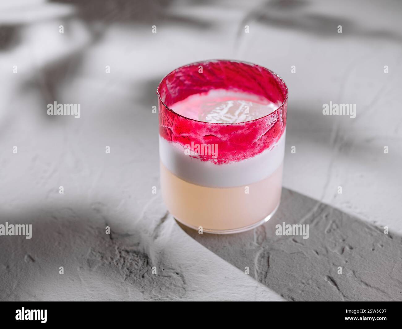 Stylish cocktail with vibrant pink and white layers, presented on a ...