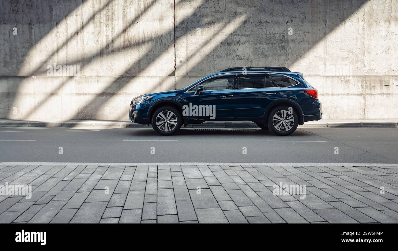 Blue Subaru Outback in front of concrete wall. Side profile view of ...
