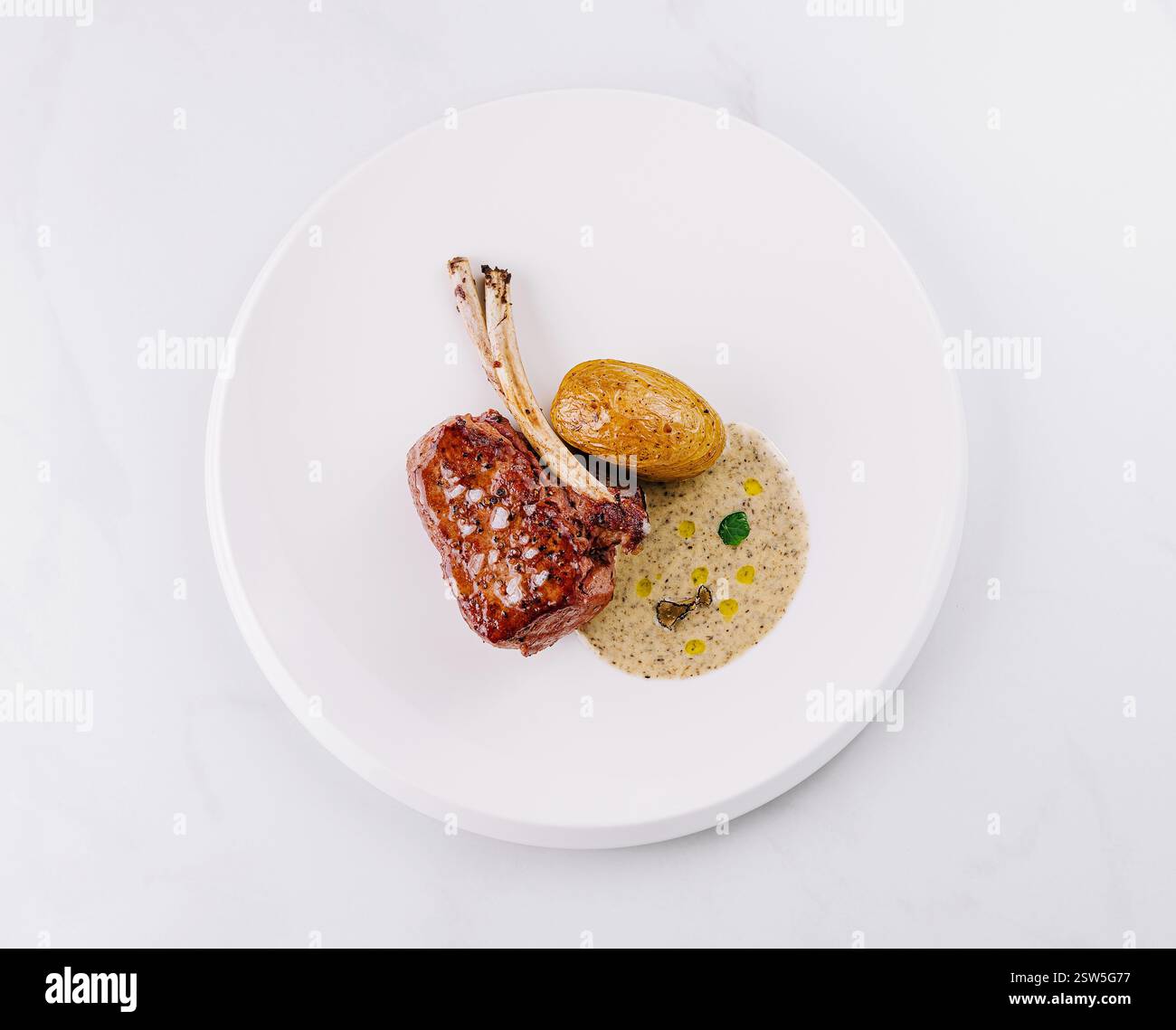 Elegant plating of a juicy lamb chop with golden roasted potatoes on a ...