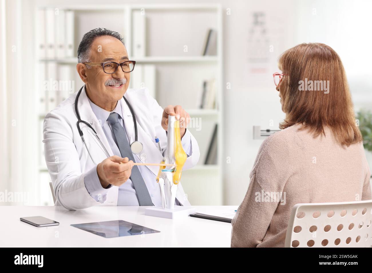 Doctor explaining a knee surgery procedure to a mature female patient ...