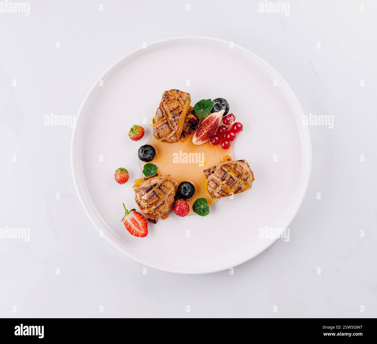Top view of a stylish meat plating with assorted berries and sauce on a ...