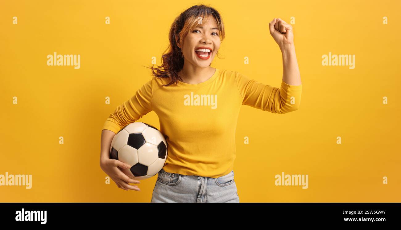 Happy asian woman football fun holding a ball and gesturing win against ...