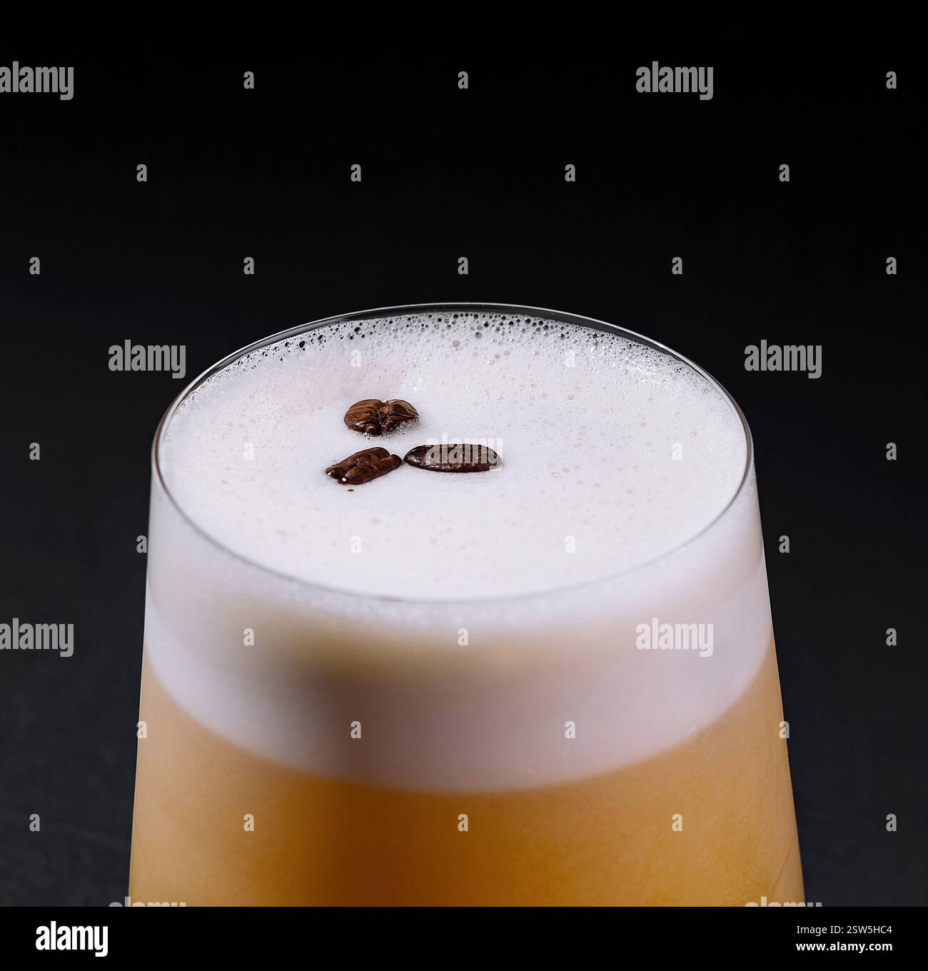 Classic whiskey sour cocktail with frothy top, served on a dark, moody ...