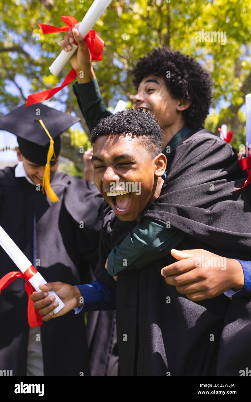 In school, graduating diverse students holding diplomas and cheering ...