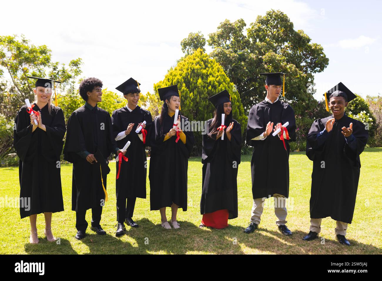 Graduating diverse students in caps and gowns celebrating success in ...