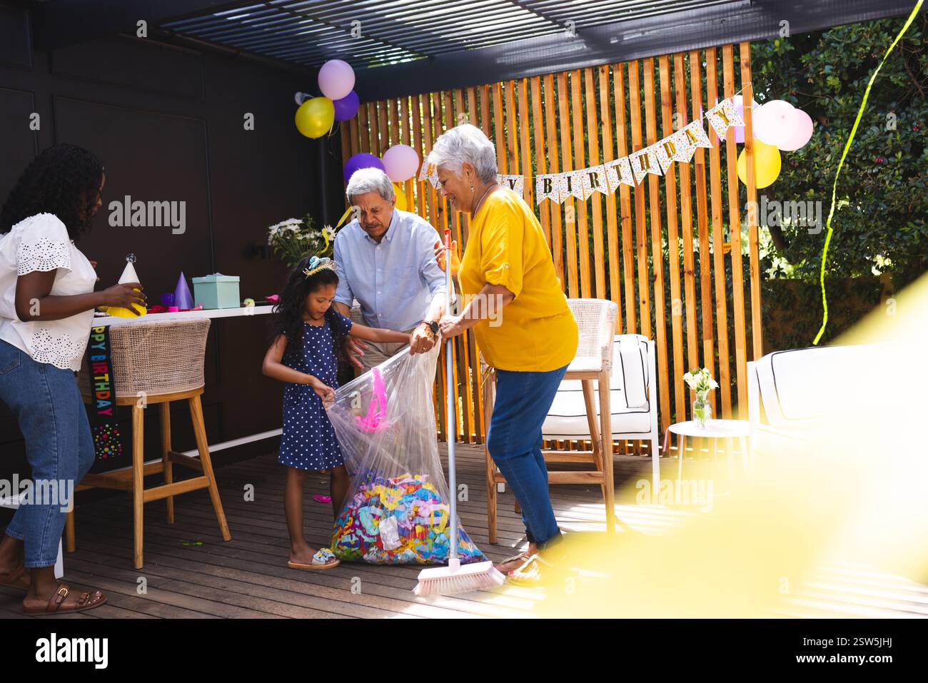 Diverse family cleaning up after birthday party on patio, enjoying time ...