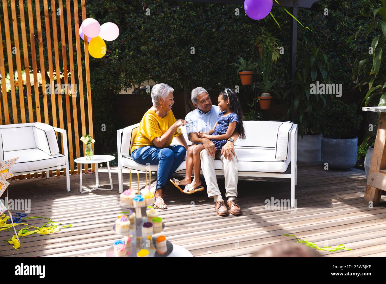 Sitting with granddaughter on patio, grandparents sharing diverse ...
