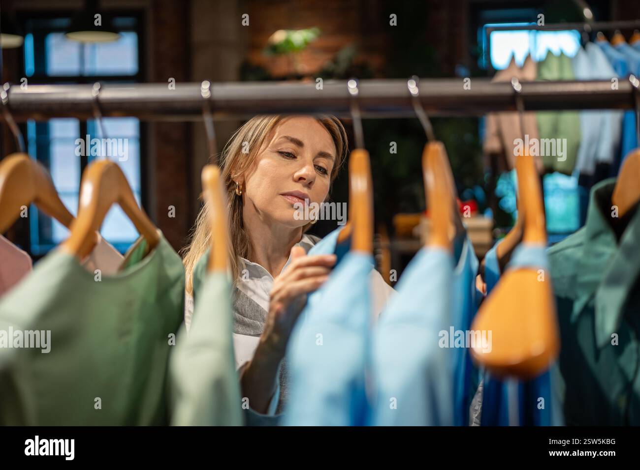 Interested focused woman shopping, choose clothing in trendy store ...