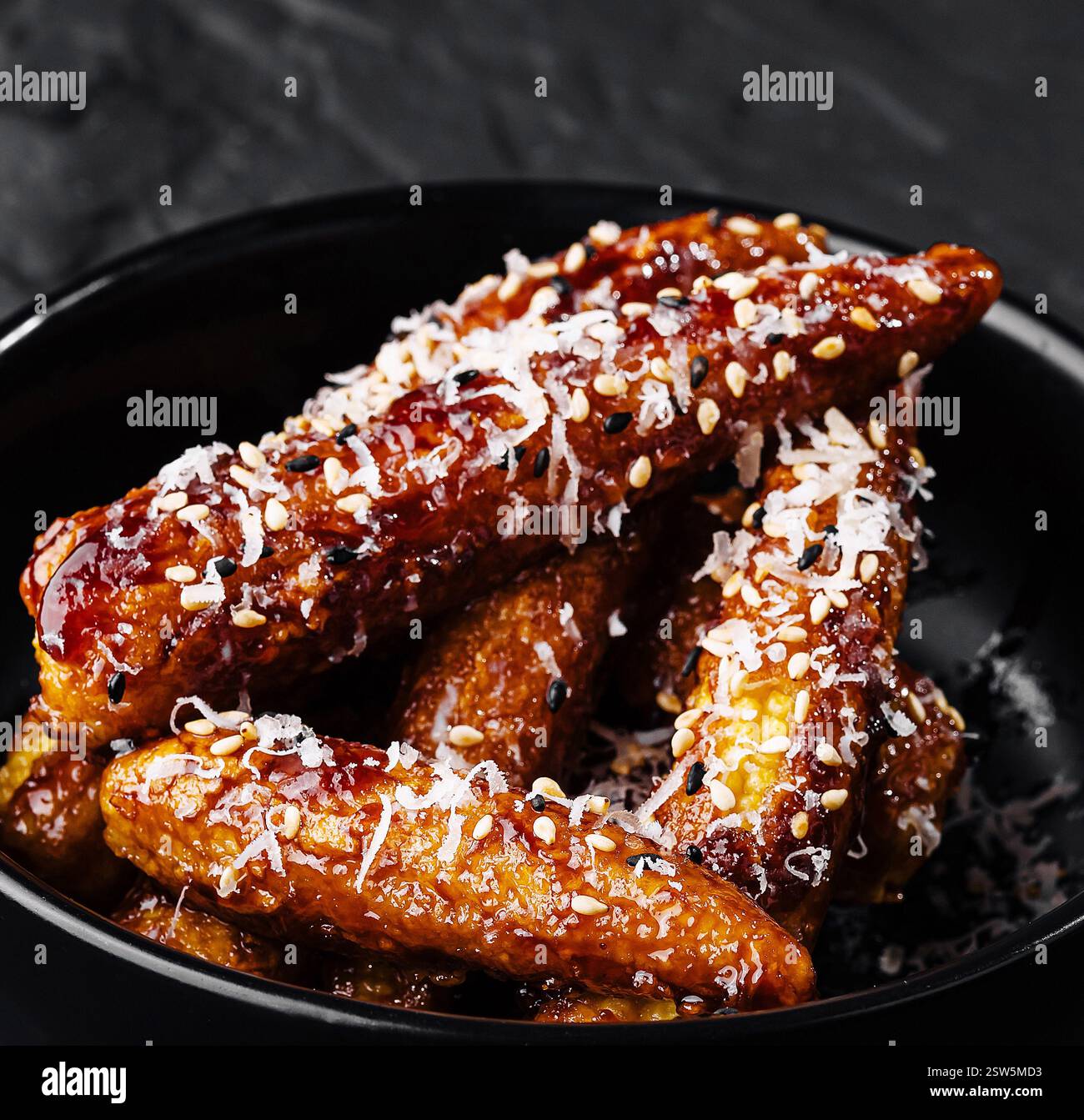 Honey glazed chicken wings in black bowl Stock Photo - Alamy