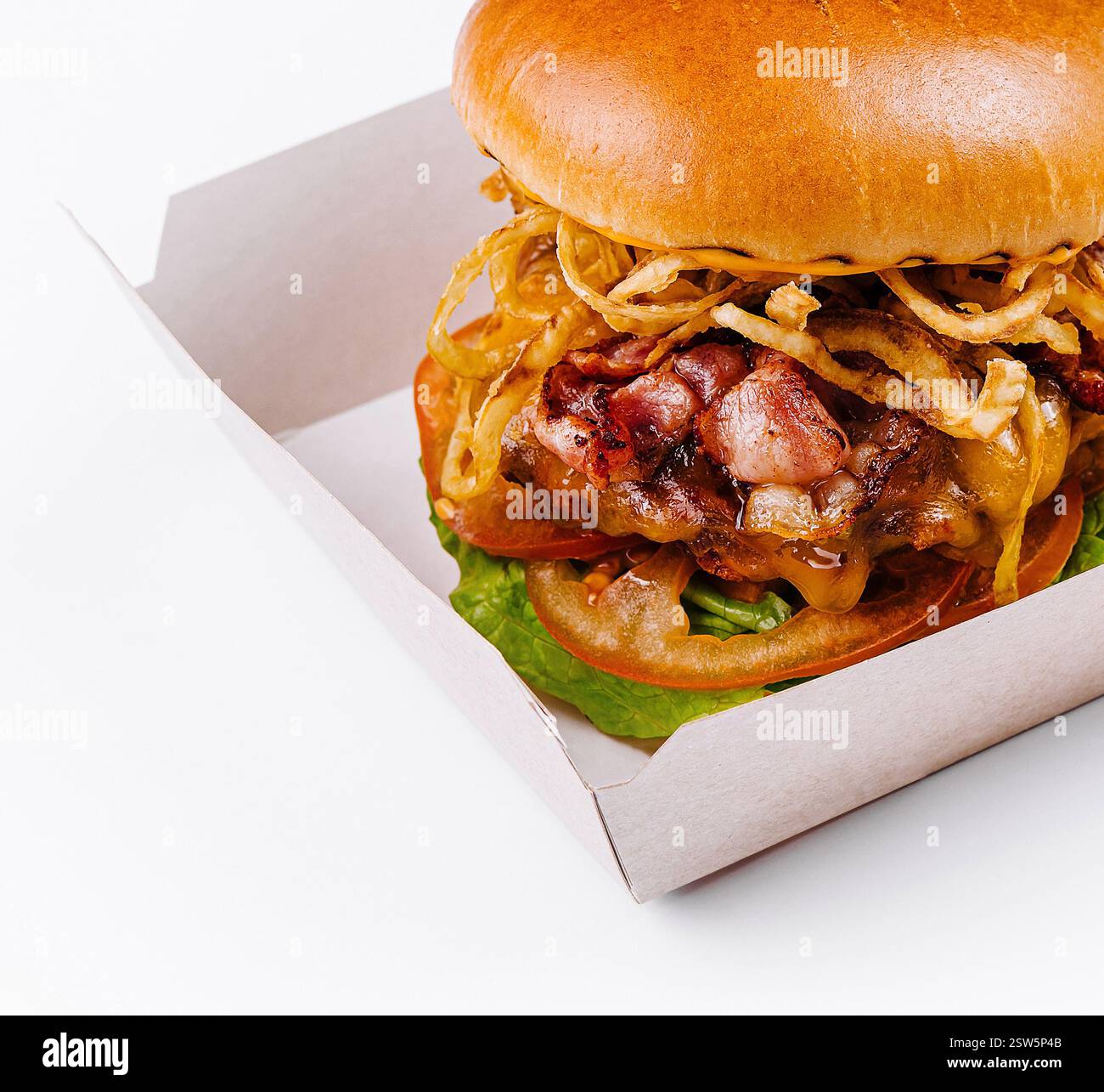 Appetizing cheeseburger with bacon and toppings in an open cardboard ...