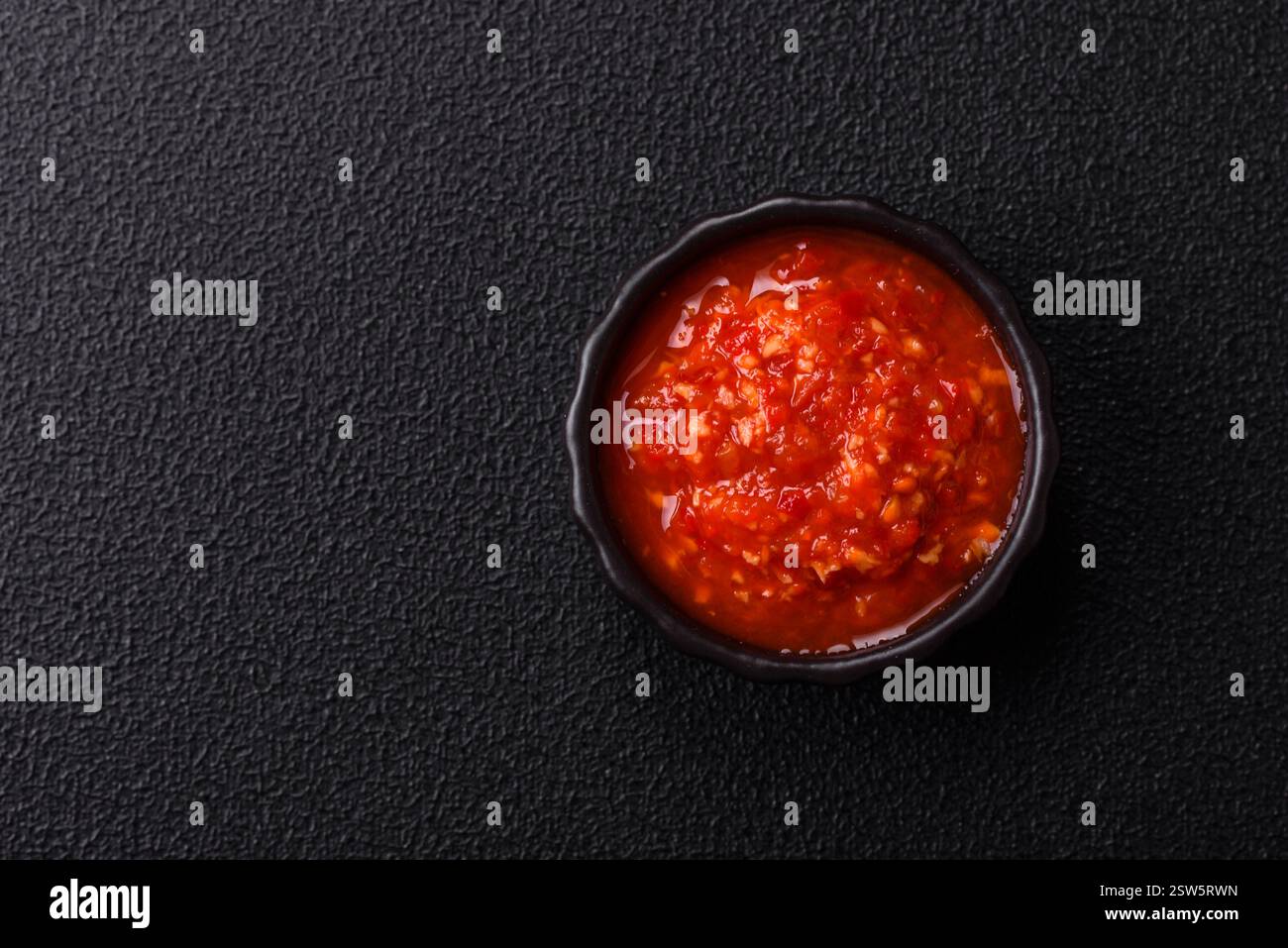 Delicious hot spicy red sauce with salt and spices in a ceramic bowl on ...